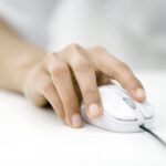 Close-up shot of a person's hand using a computer mouse