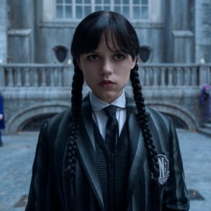 young dark-haired girl in pigtails wearing a black school uniform looking dour