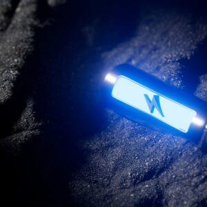 Image of a black, powdery surface with a glowing blue battery on it.