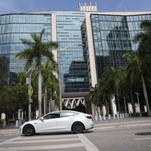 A white Tesla outside a glass building