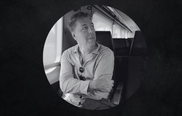 A man sits in a chair with his arms crossed