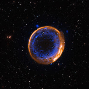 Image of a dark background punctuated with stars, with a bright ring in the center that is comprised of an outer orange and inner blue ring.
