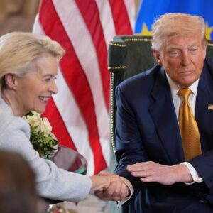 US President Donald Trump and European Commission President Ursula von der Leyen sit in chairs and shake hands .