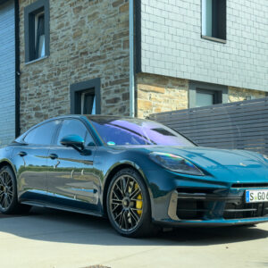 A blue Porsche Panamera Turbo S next to a farmhouse