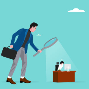 Illustration of a boss using a magnifying glass to watch a physically smaller employee sitting at an office desk.