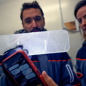 Two scientists in cold-weather gear hold up a cylinder of ice in a lab.