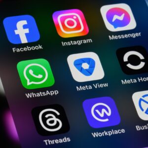 A phone screen displays app icons for Meta apps Facebook, Instagram, Messenger, WhatsApp, Meta View, Meta Horizon, Threads, Workplace, and Business Suite.
